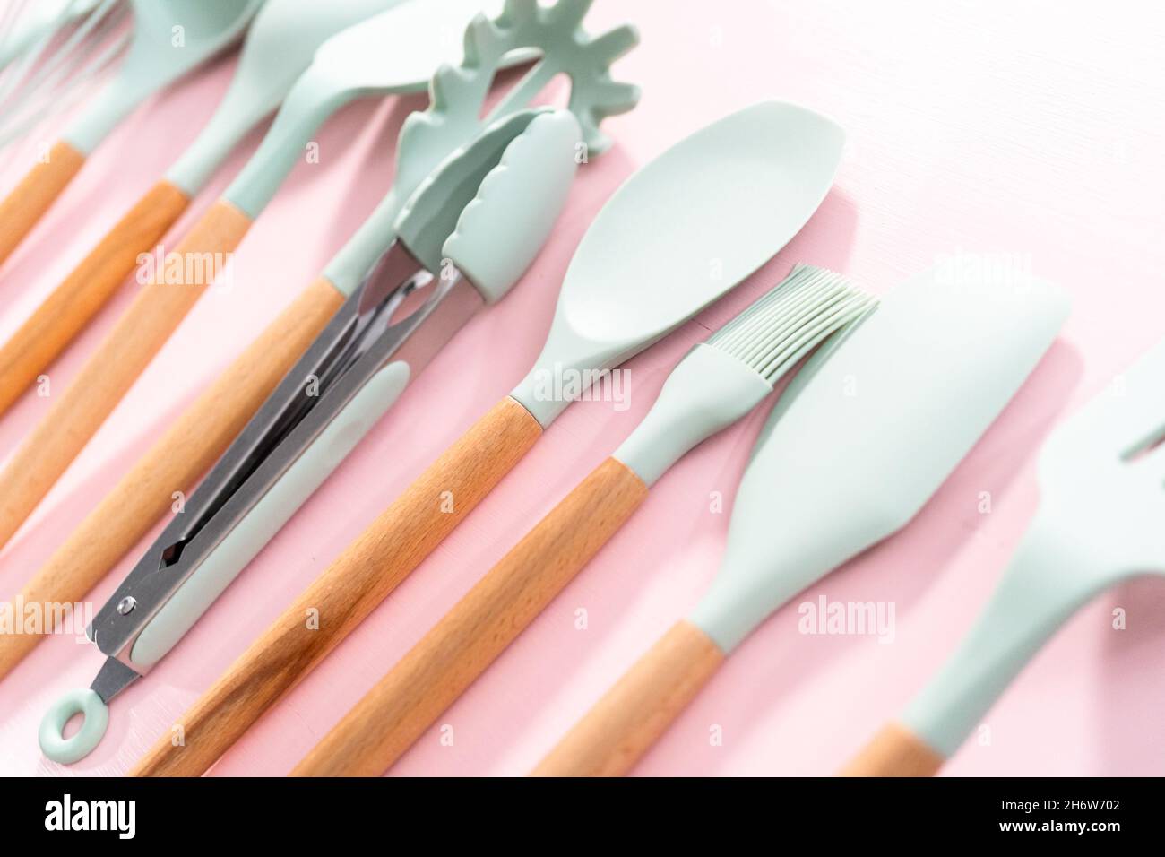 New blue silicone kitchen utensils with wooden handles on a pink ...