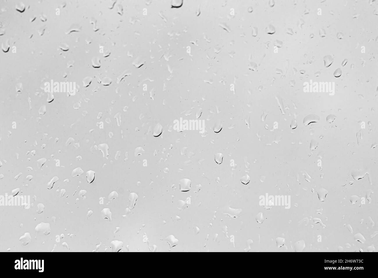 Rain drops on window glasses surface with gray sky background. Natural ...