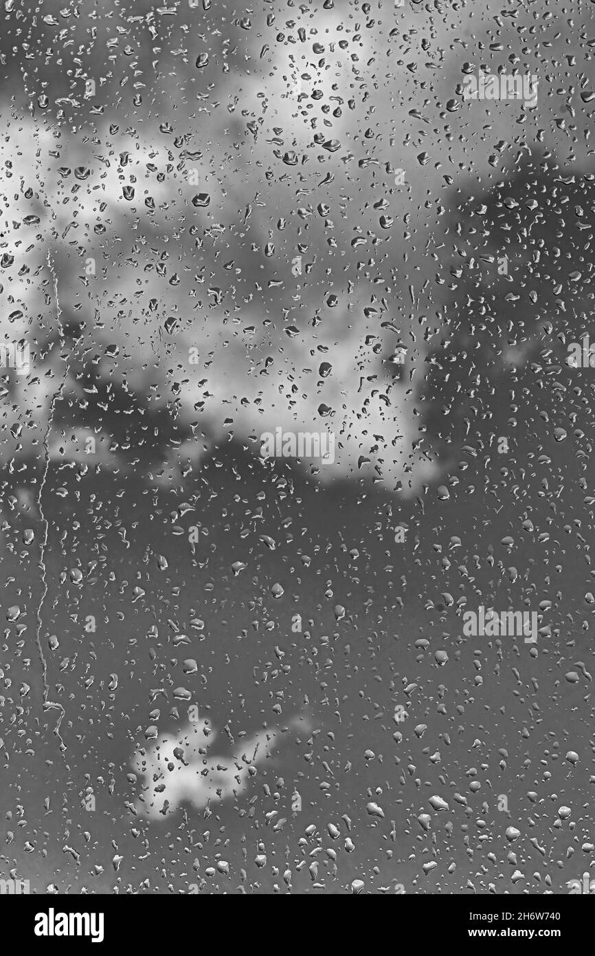 Rain drops on window glasses surface with gray sky background. Natural ...