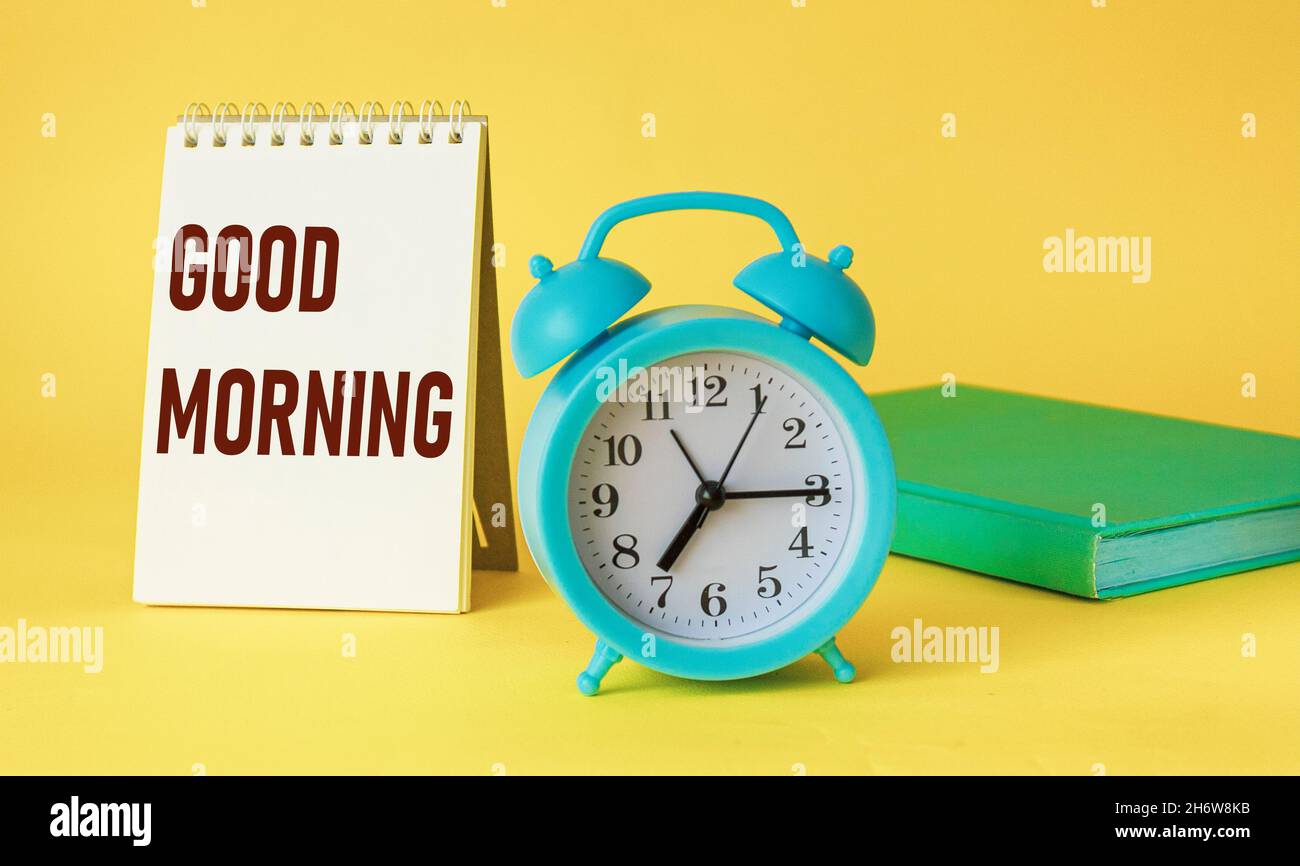 Clock and notepad with the text Good morning on a yellow background ...