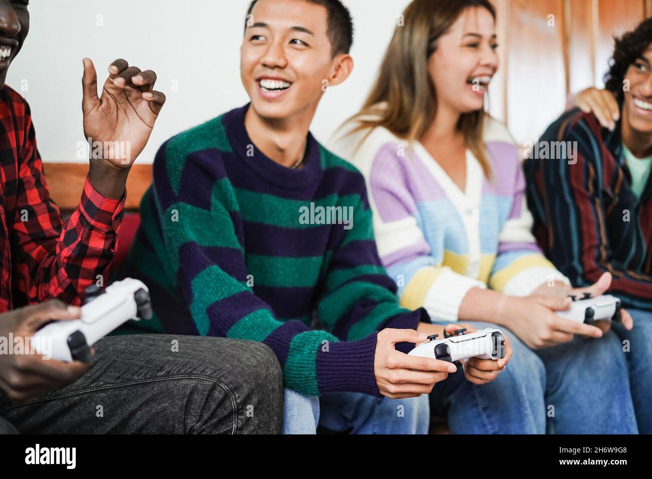 Multiracial young friends having fun playing video games at home ...