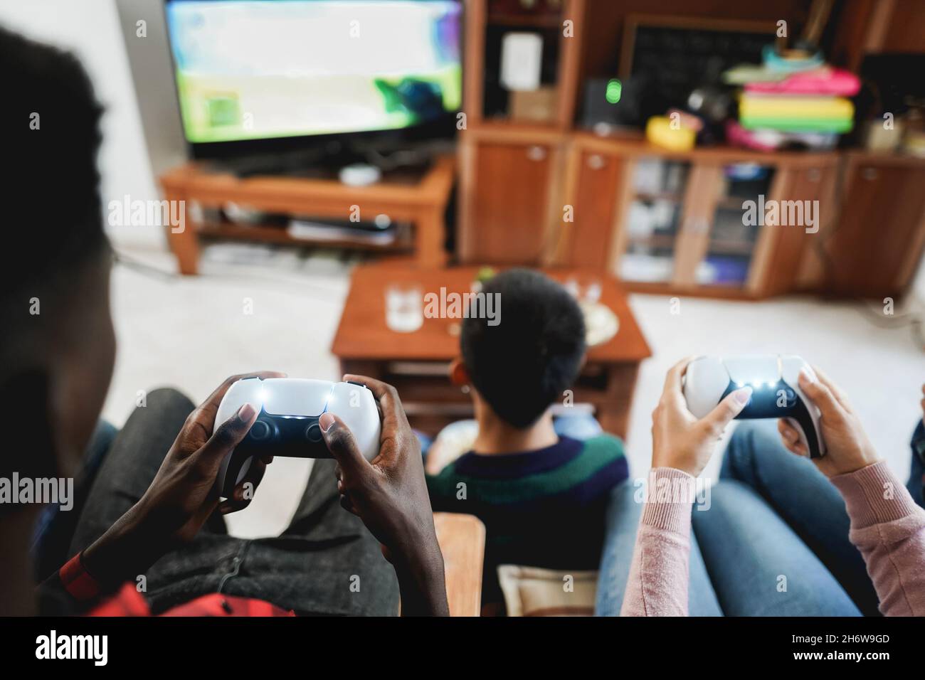 Multiracial young friends having fun playing video games at home ...