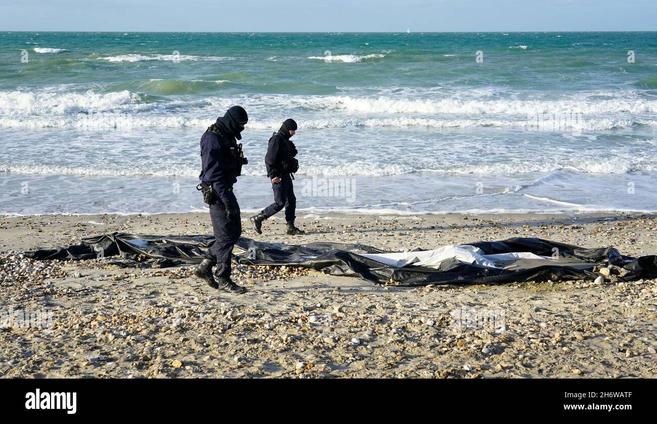 French police officers pass a deflated dinghy on the beach in Wimereux ...