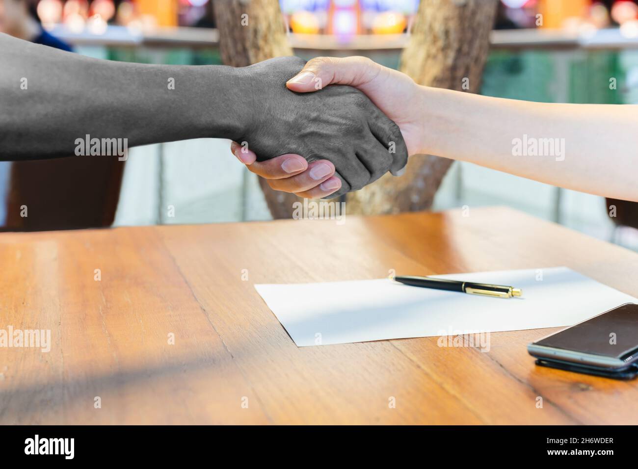 White and Black man hand shaking hands after signing of business ...