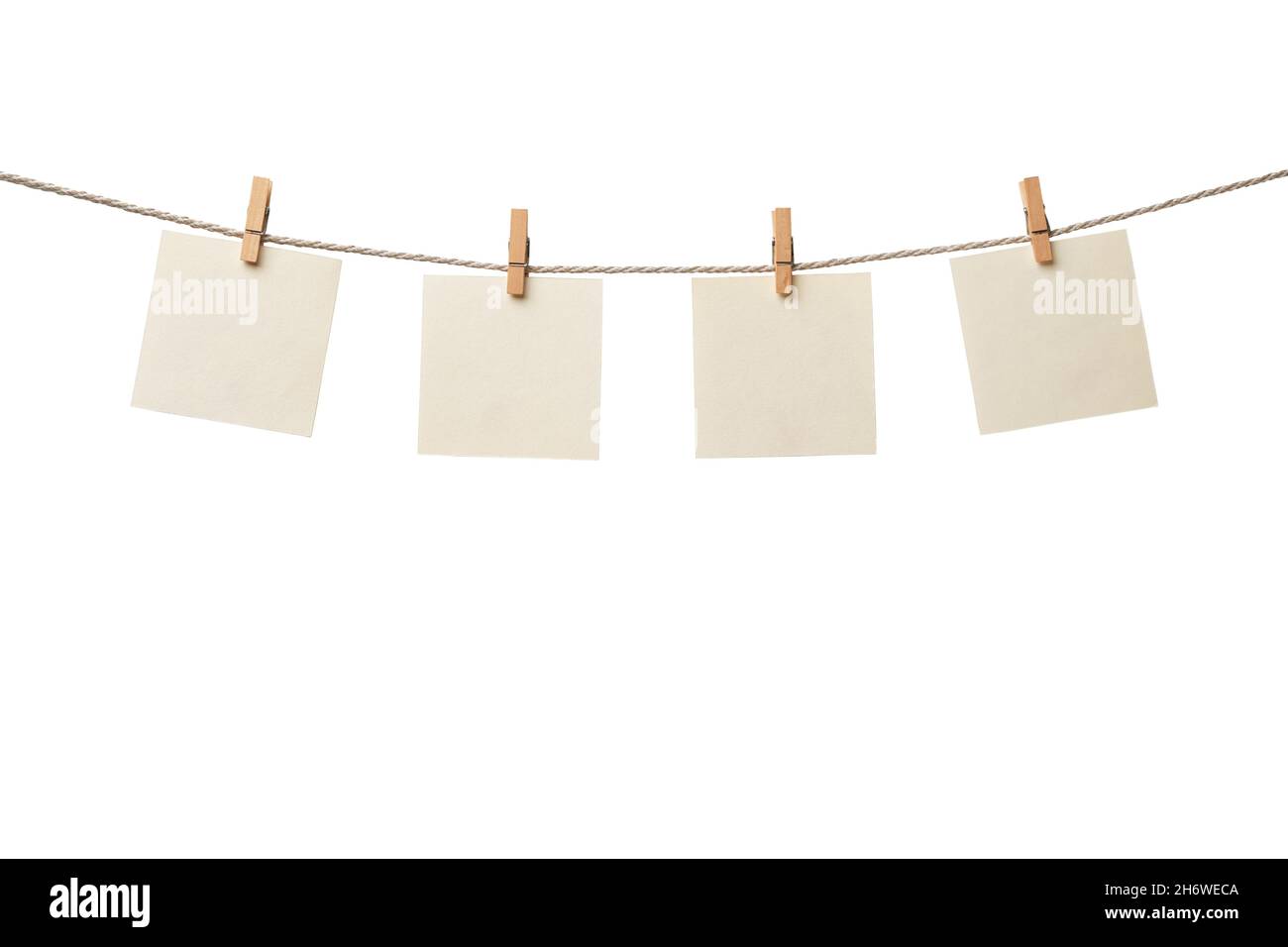 Four old paper blank notes hanging on the rope with wooden clothespins ...