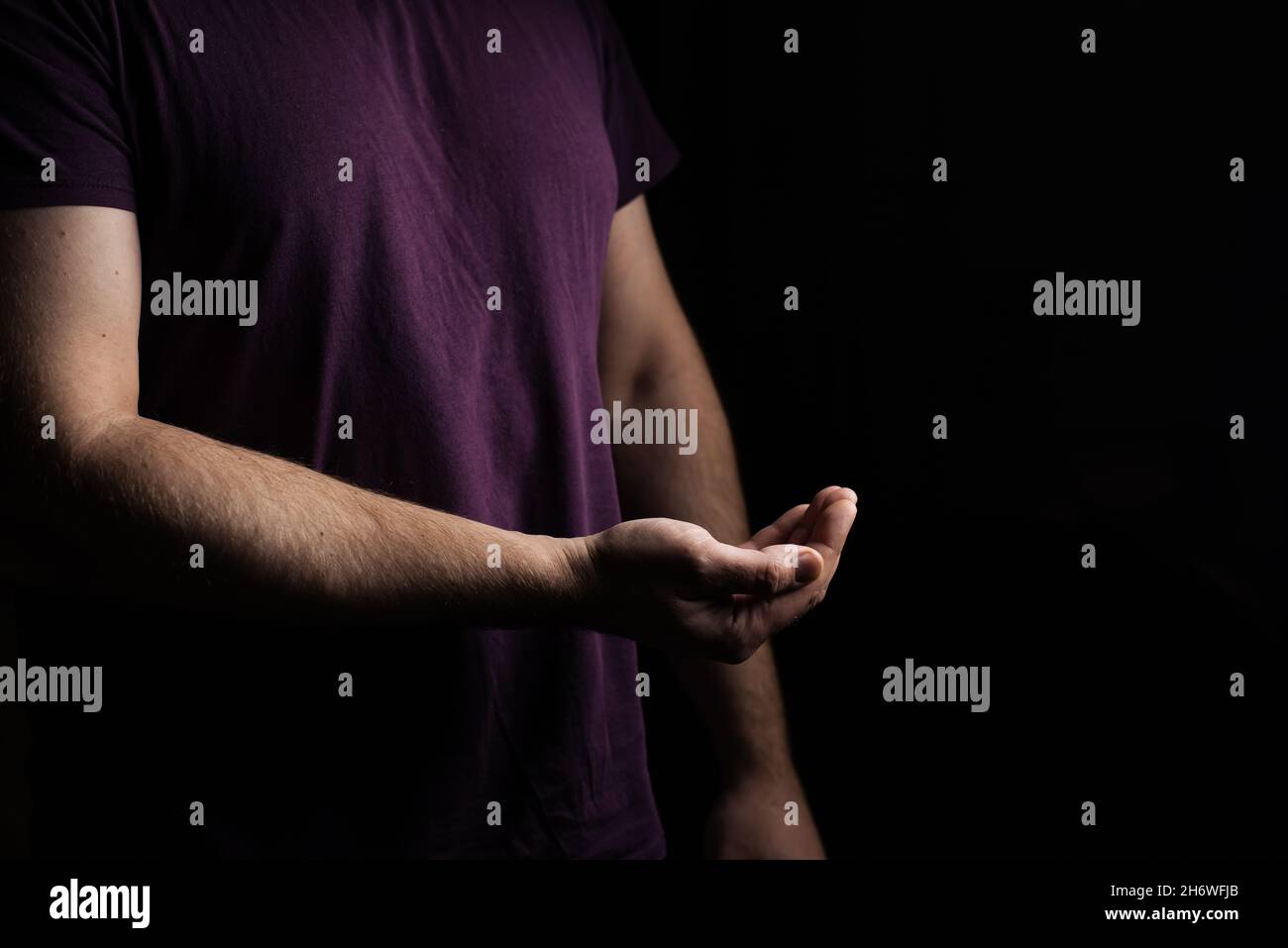 Empty male hand, palm up on a black background. Giving, asking concept ...