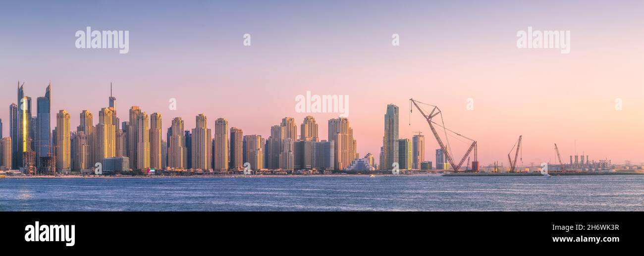 Modern buildings with gold reflection of sunset on Dubai Marina bay ...