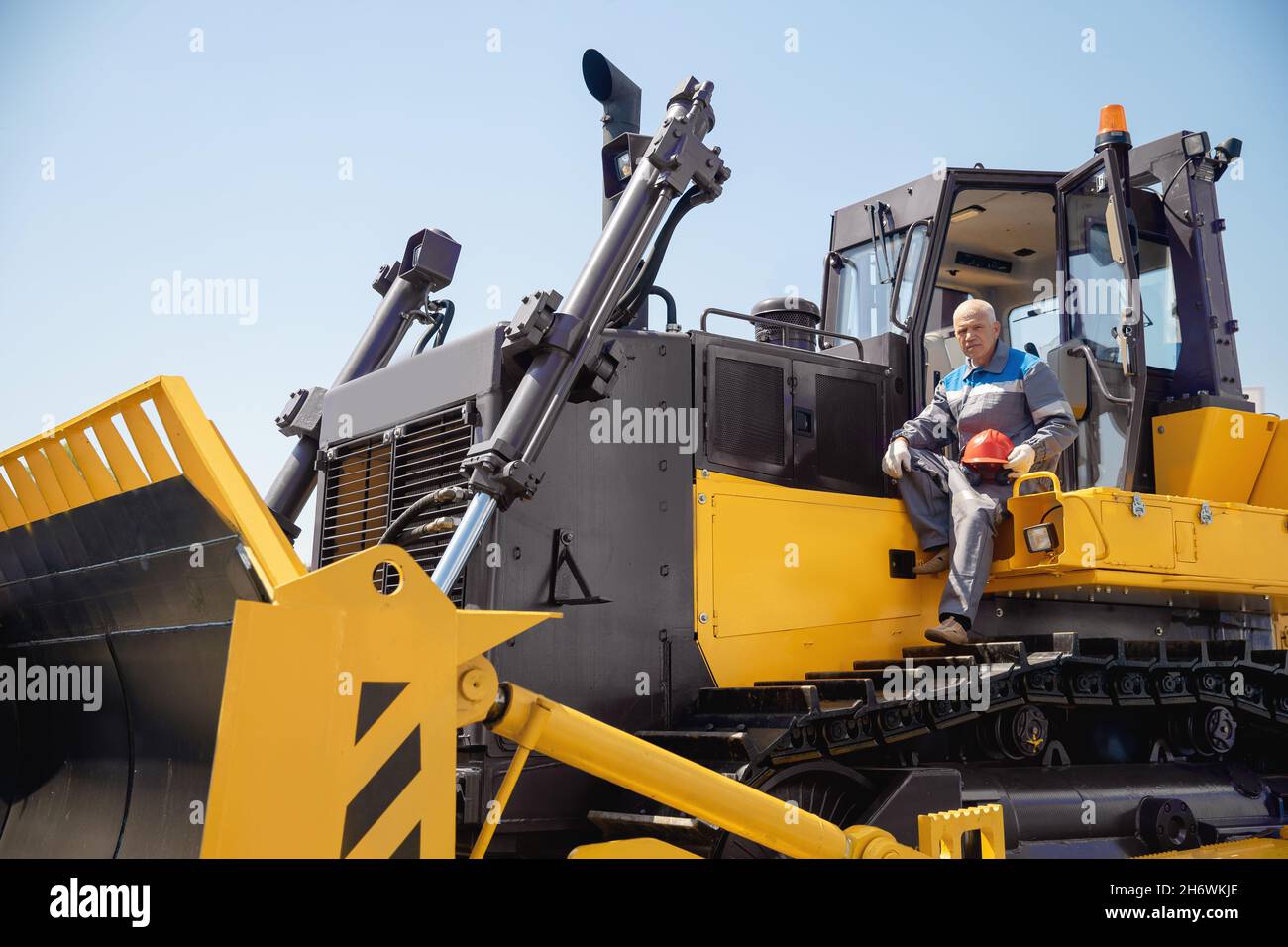 Industrial portrait of working man, excavator driver climbs into cab to ...