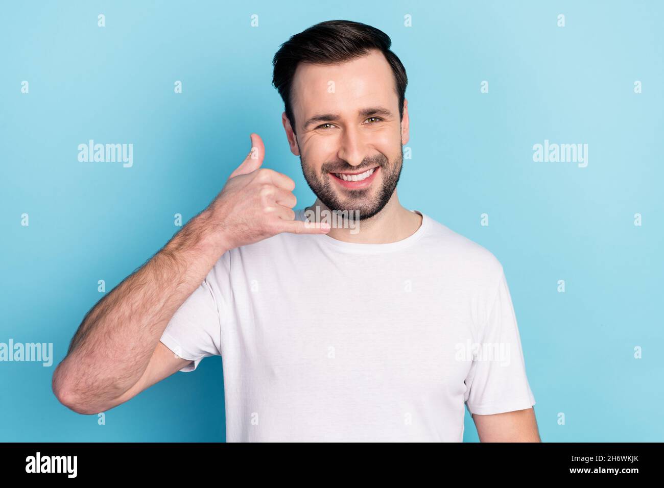 Portrait of attractive cheerful guy showing call me sign answer ...
