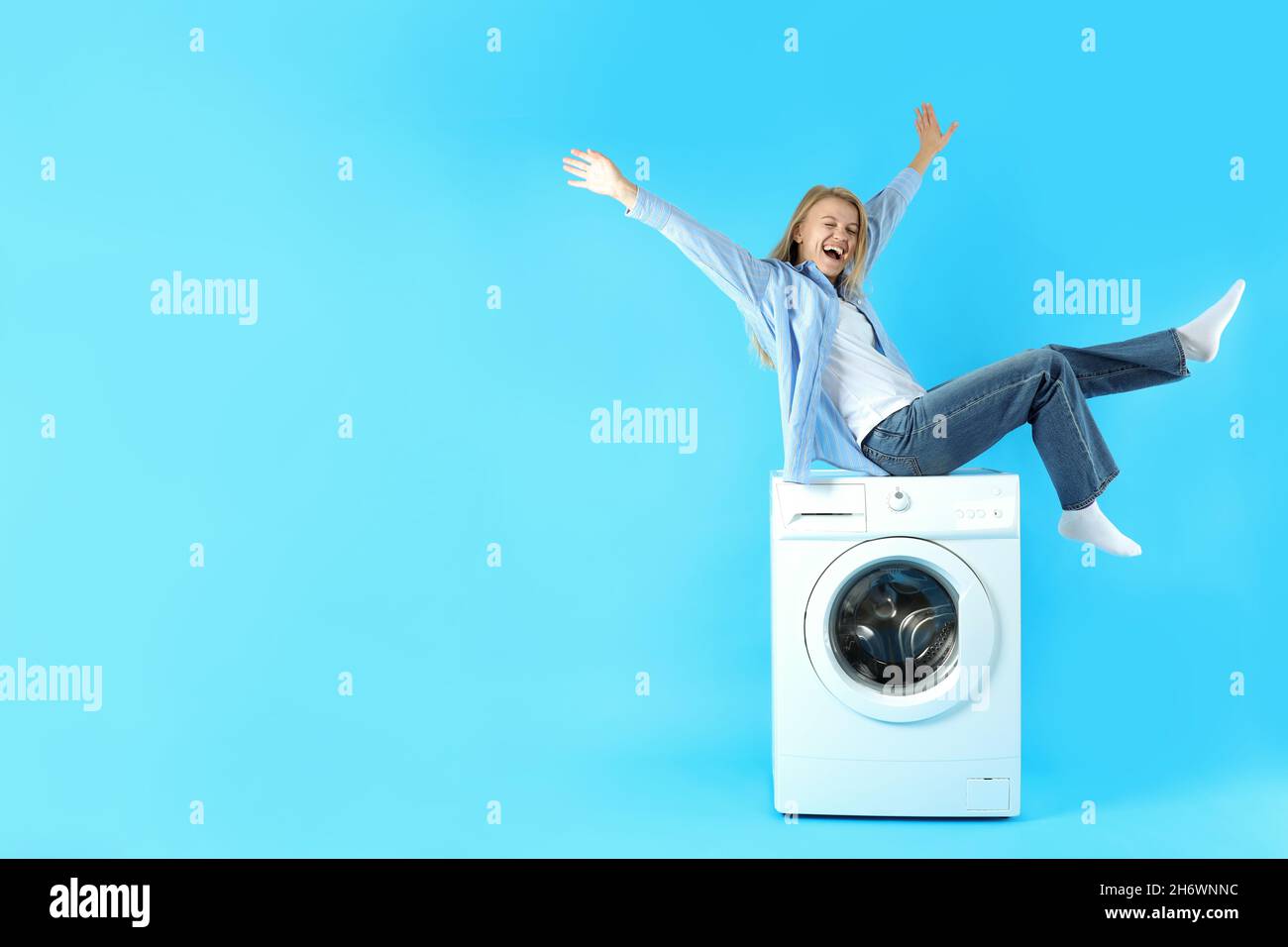 Concept of housework with washing machine and girl on blue background ...