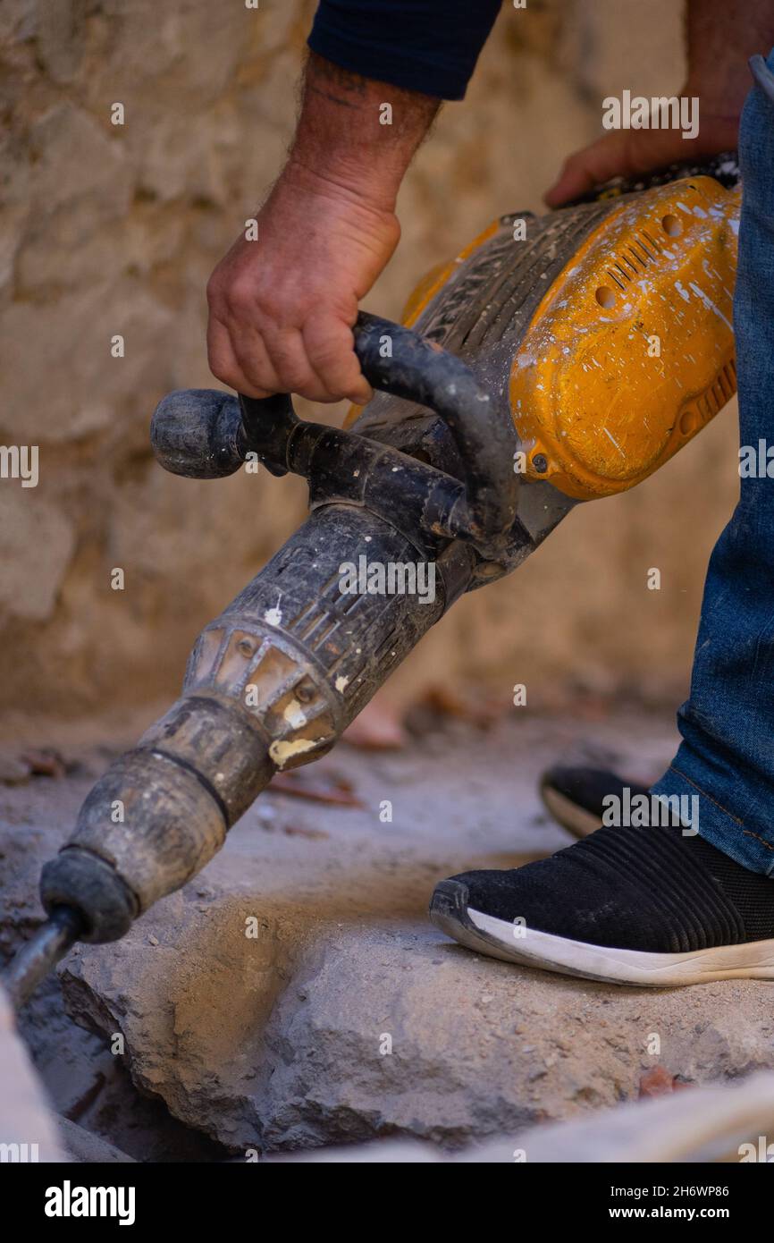 construction site worker with drilling machine removing the ground ...
