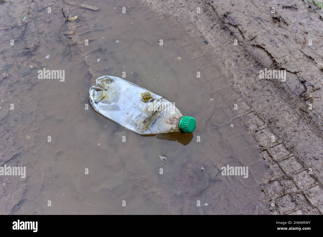 A plastic bottle is thrown into a puddle on the ground. Environmental ...