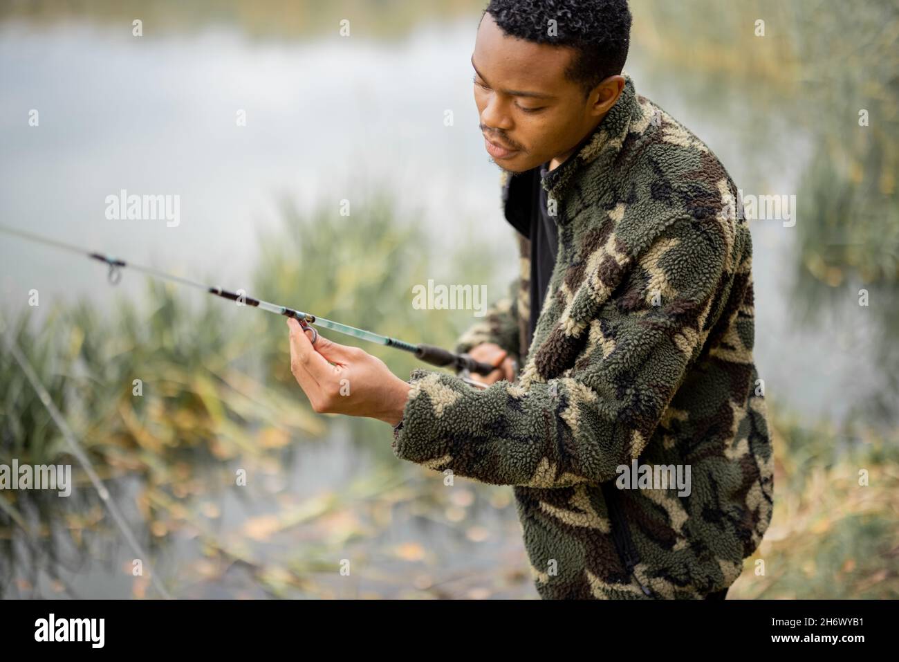 Man correct fishing rod at fishing on lake coast Stock Photo - Alamy