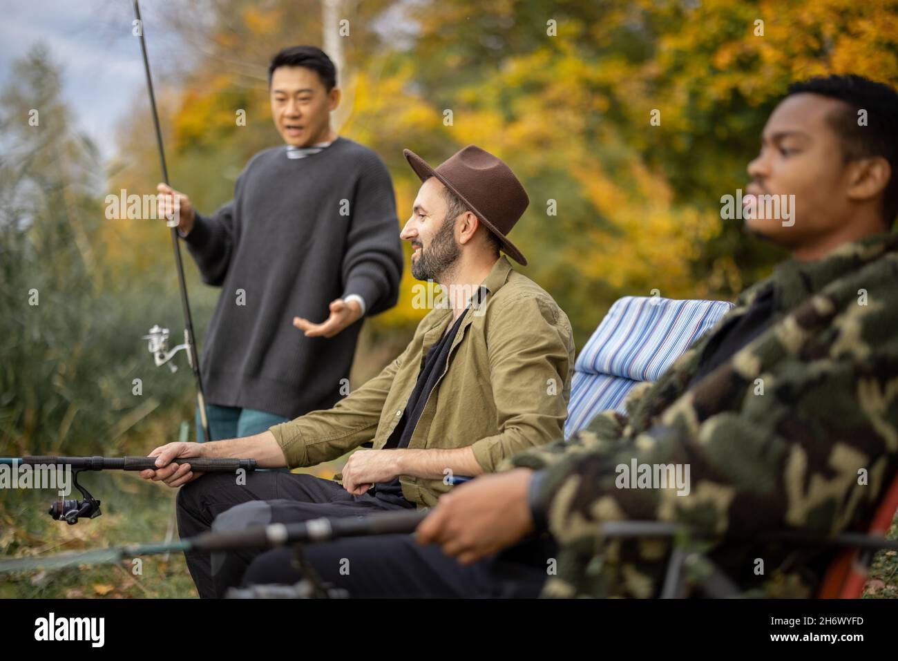 Man talking to male friends at fishing in nature Stock Photo - Alamy