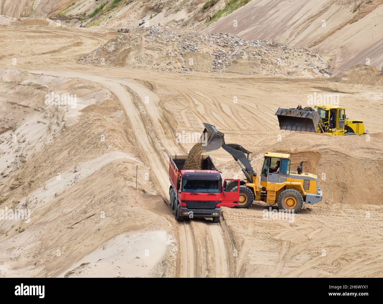 Wheel loader loading sand into heavy dump truck at the opencast mining ...