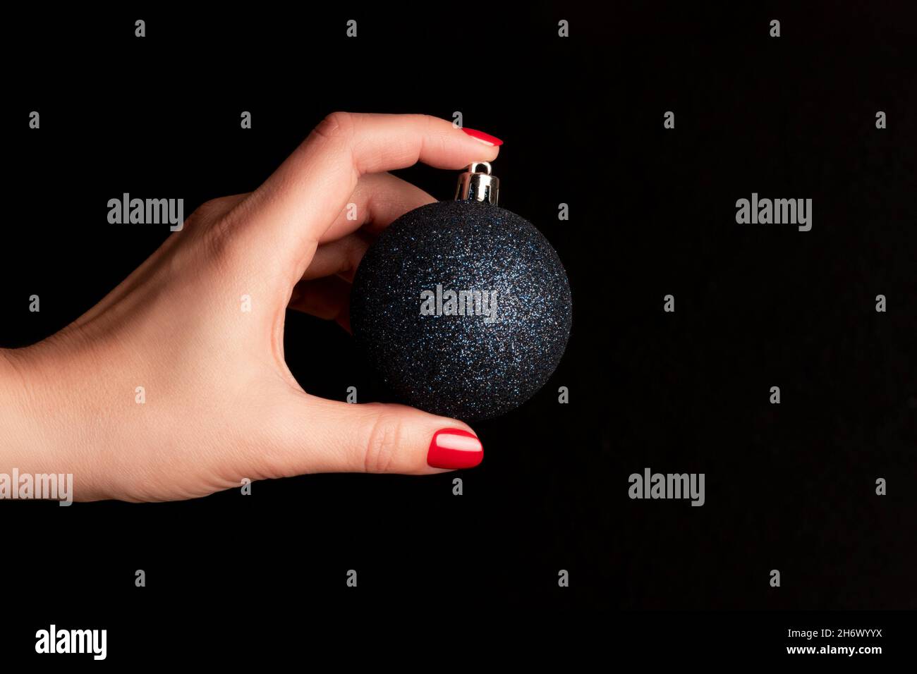 Female hand with blue glittery Christmas ball with beautiful manicure ...