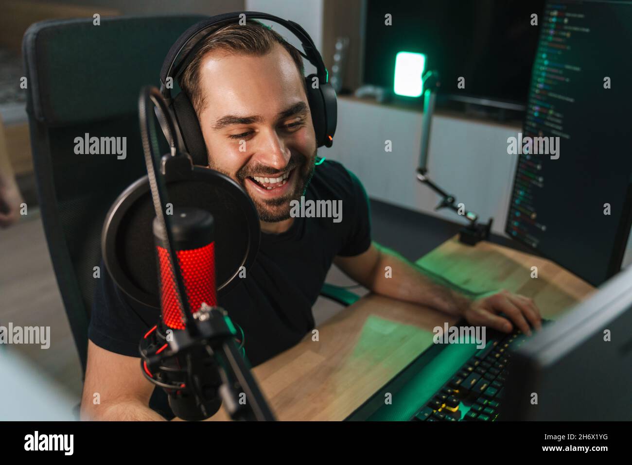 Happy young man gamer streamer in headphones playing on computer ...