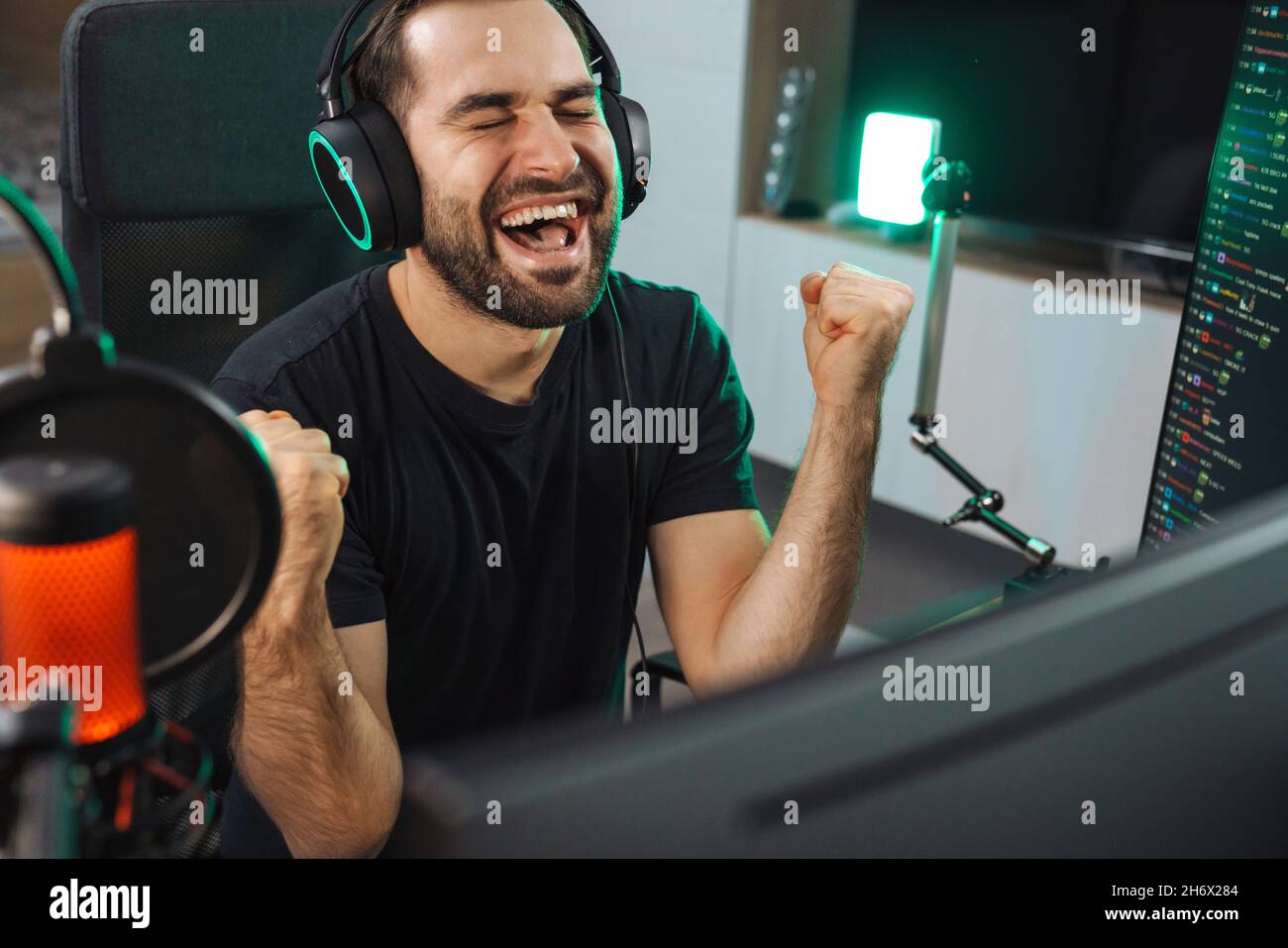 Happy young man gamer streamer in headphones playing on computer ...