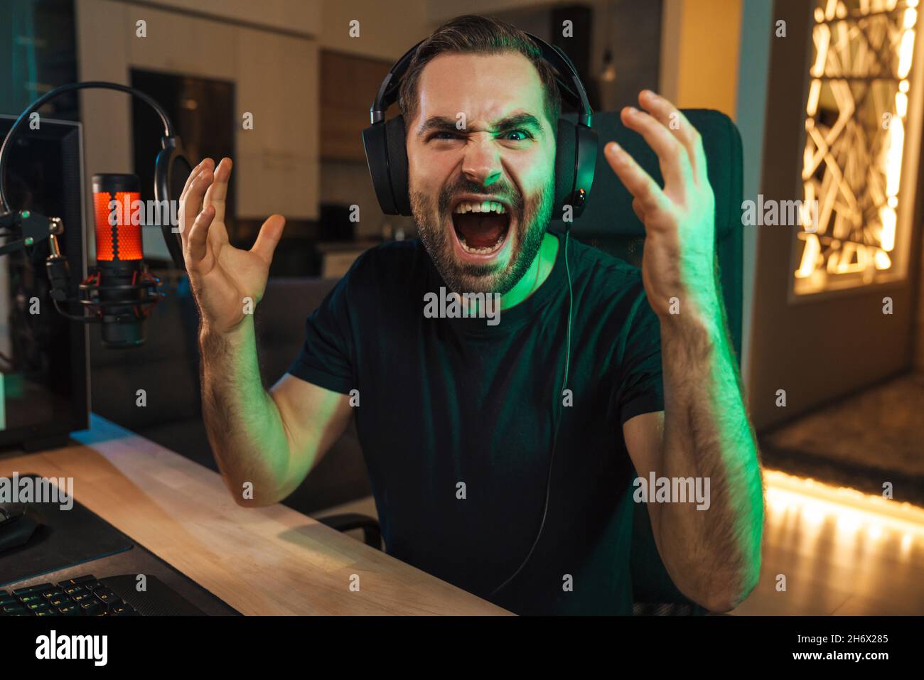 Angry devastated young man gamer wearing headphones lost a game on ...