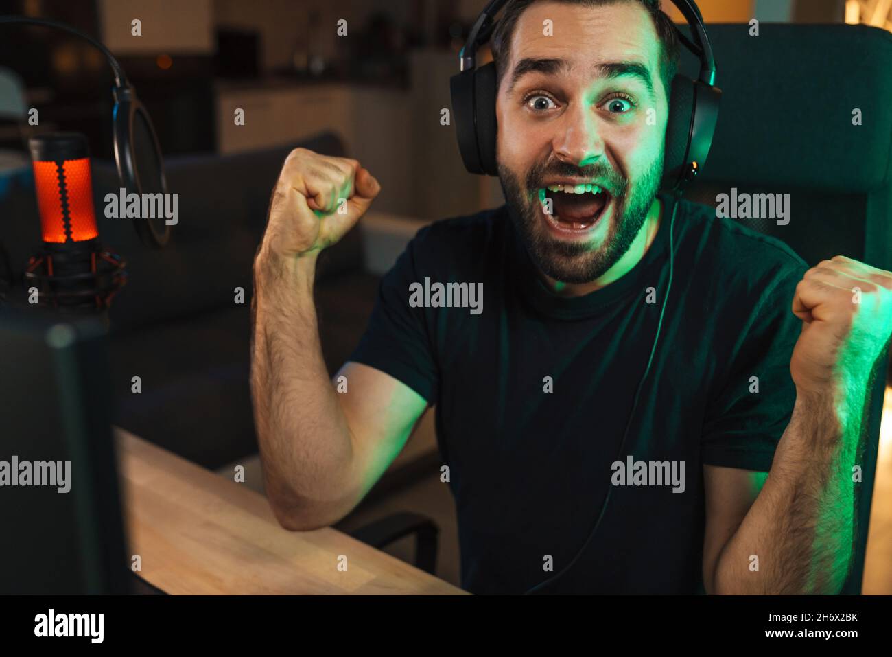 Happy young man gamer streamer in headphones playing on computer ...