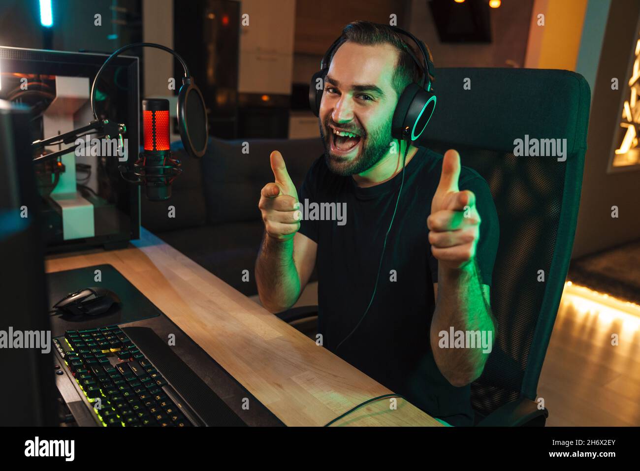 Happy young man gamer streamer in headphones playing on computer ...