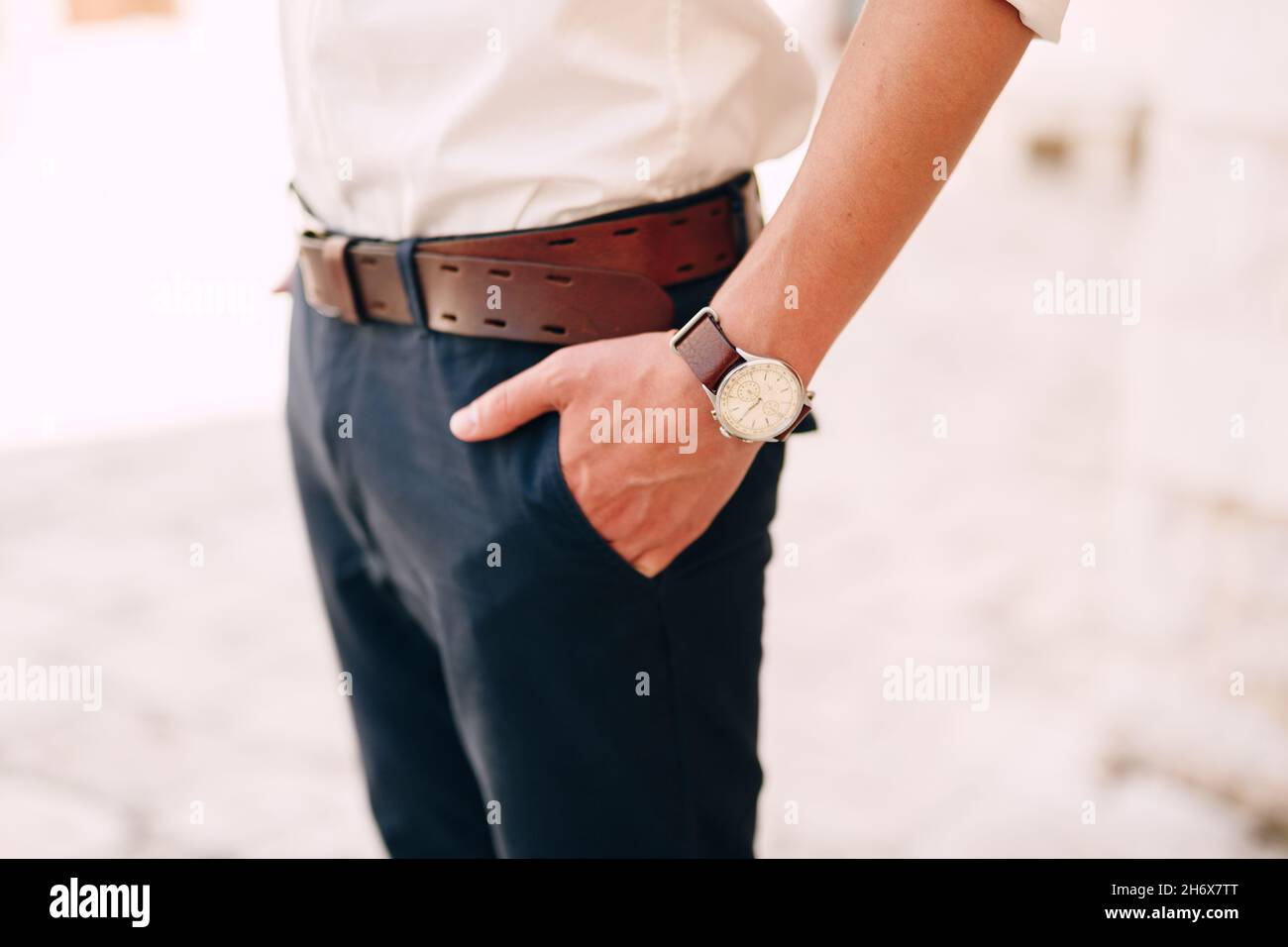 Man in a white shirt with sleeves rolled up, with a watch on his wrist ...