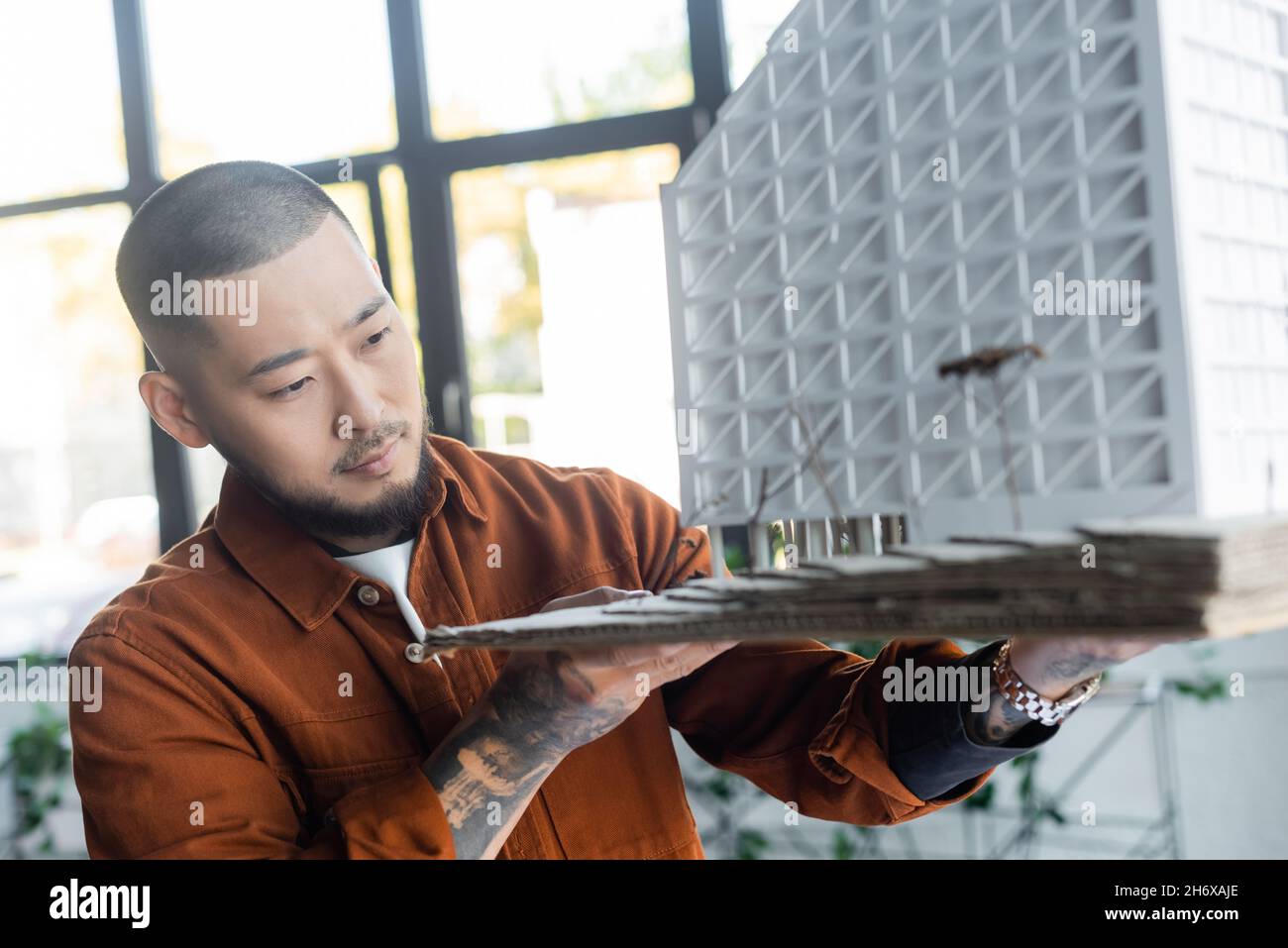 asian architect holding blurred house model while working in office ...