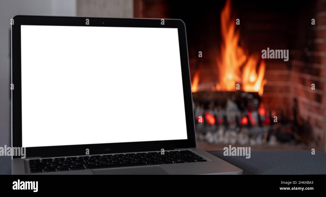 Winter home office concept. Blank screen laptop on burning fireplace ...