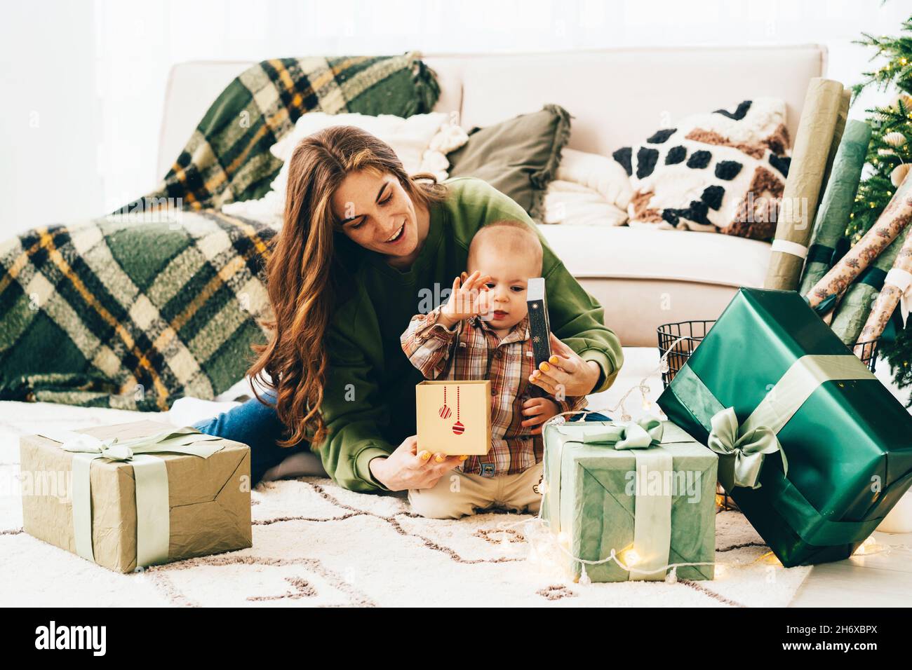 Mom with a small child open Christmas gift boxes in the living room ...