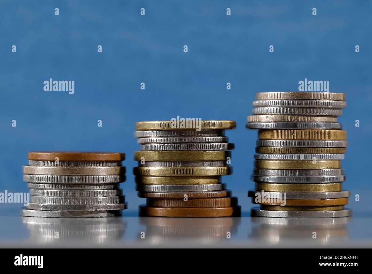 Stacked various coins in three piles and are shown against blue ...
