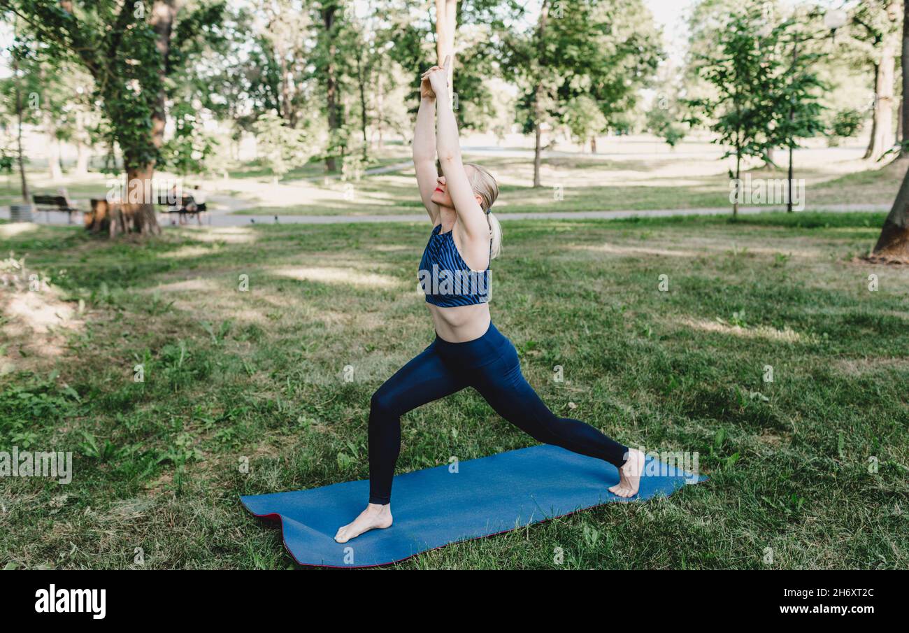 A woman practicing yoga asanas outdoors. A young attractive slender ...