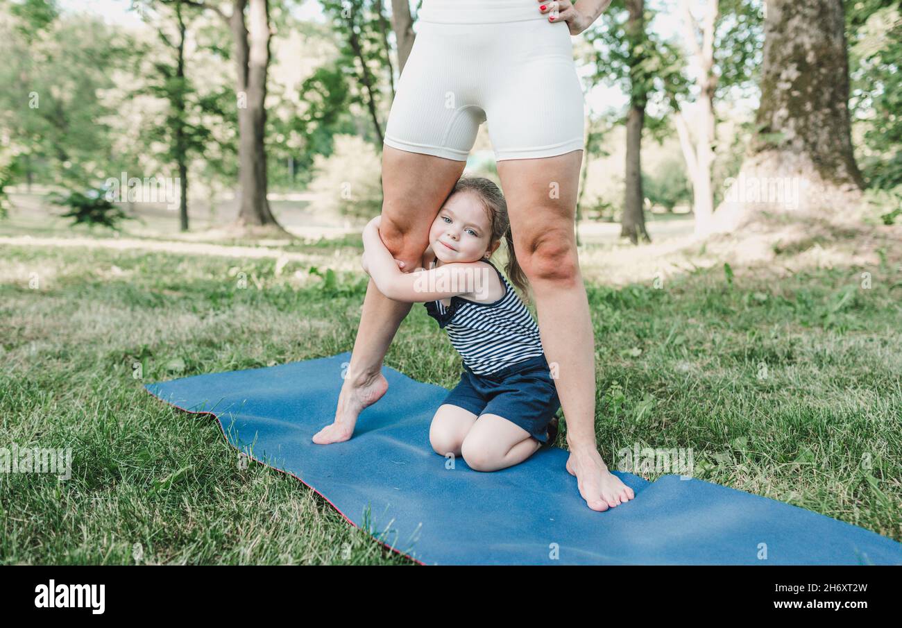 a little girl hugs her mom 's leg during a workout in the park ...