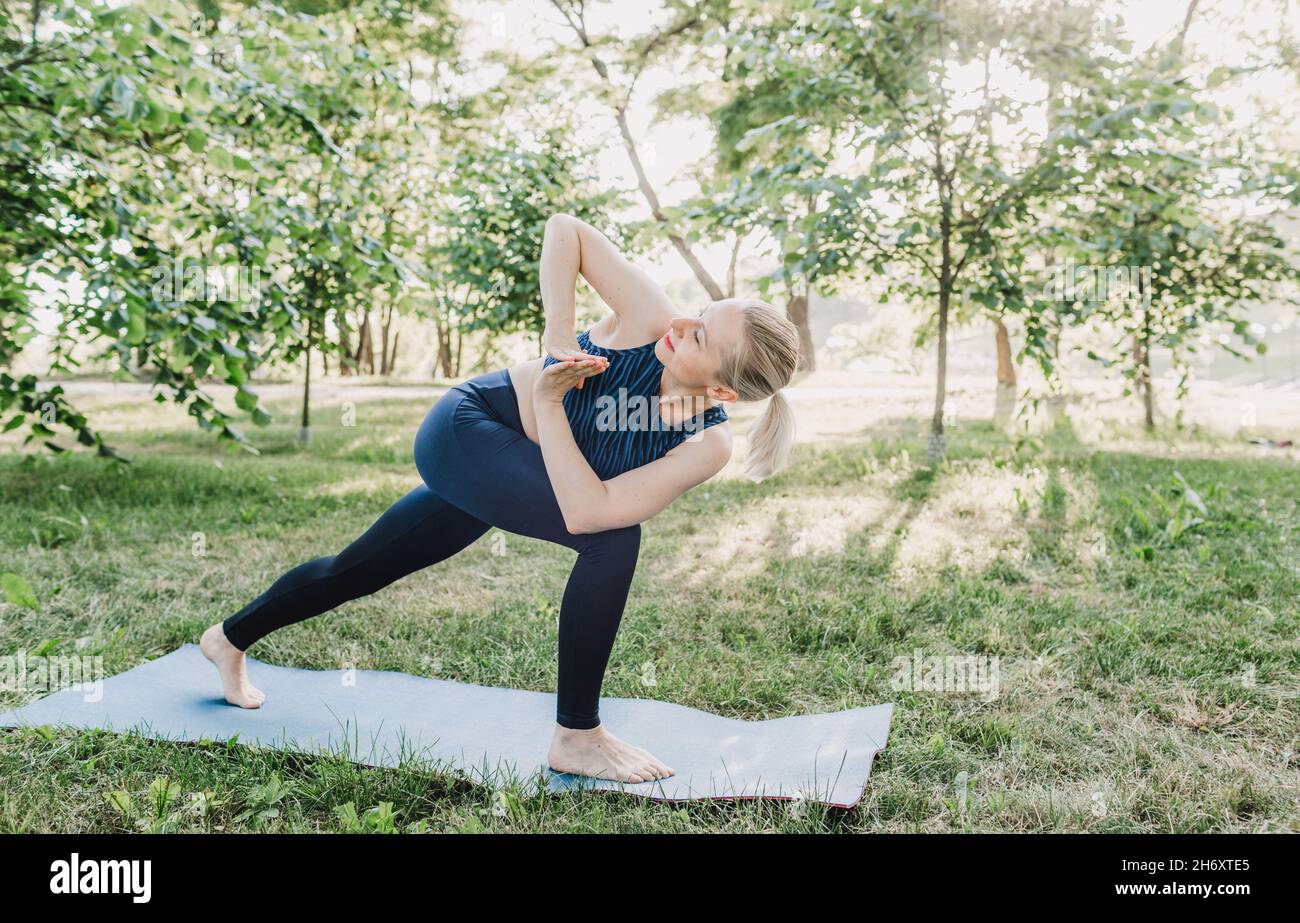 A woman practicing yoga asanas outdoors. A young attractive slender ...
