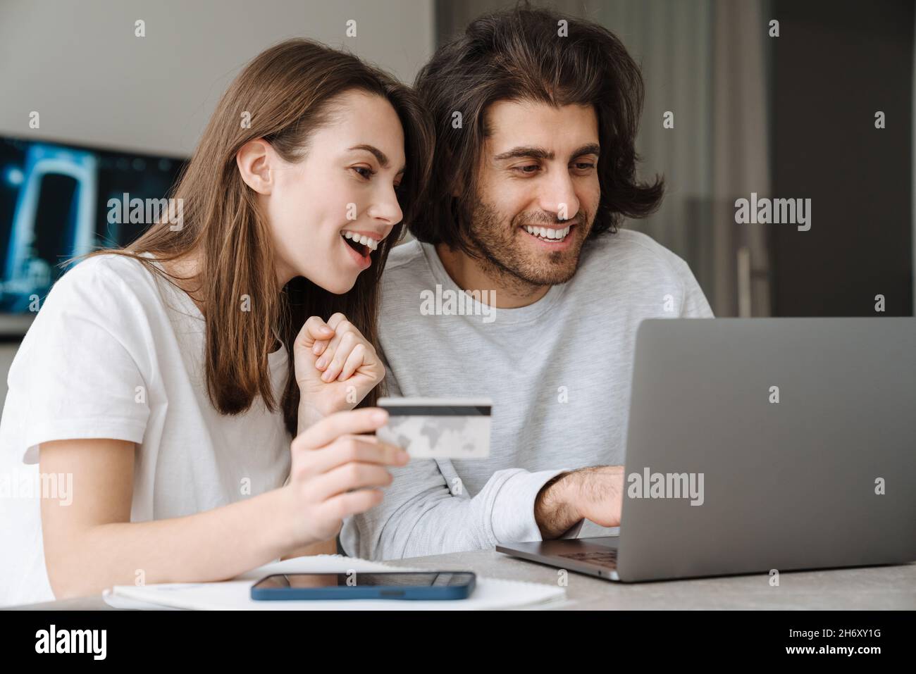 Young multiracial couple using credit card while working with laptop ...