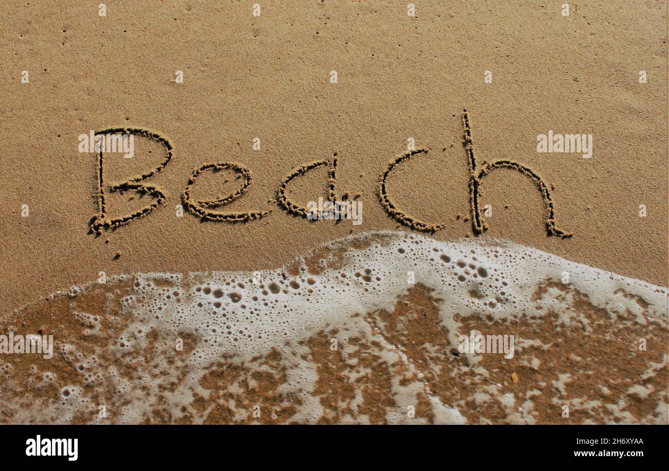 On the beach, the words Beach are carved in letters in the smooth sand ...