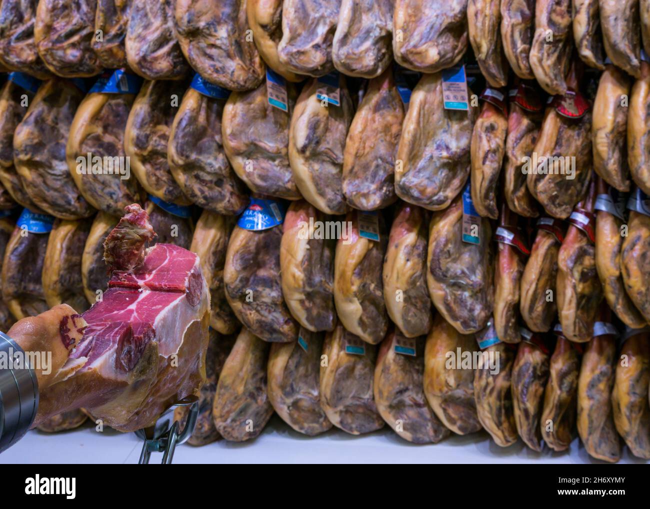 Spanish smoked Iberico & Serrano ham legs hanging in supermarket ...