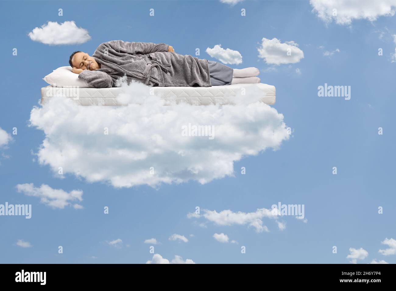 Mature man sleeping on a matress and floating in a blue sky with clouds ...