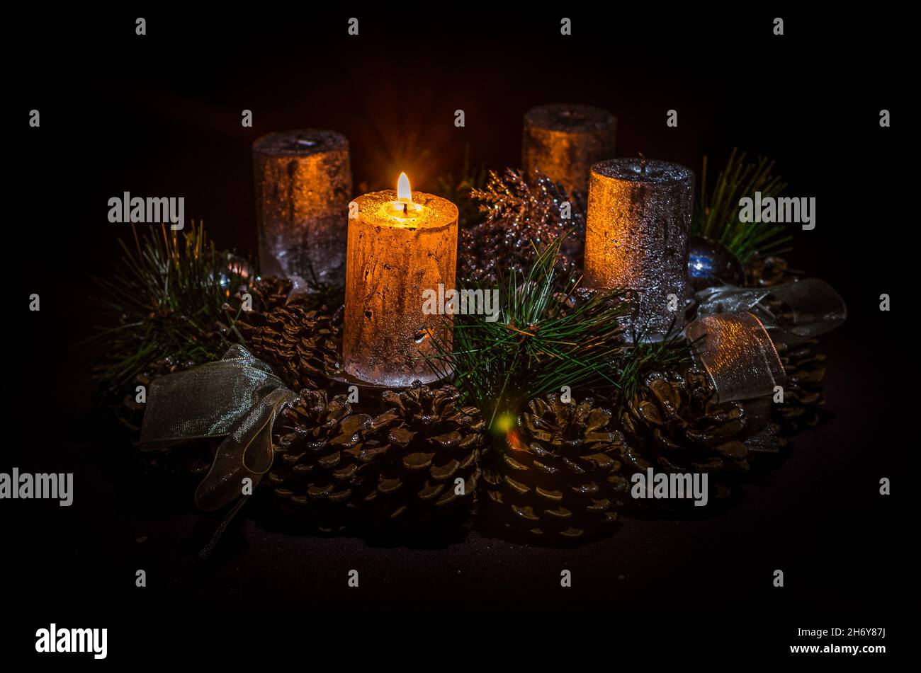 advent concept with first silver burning candle on black background ...