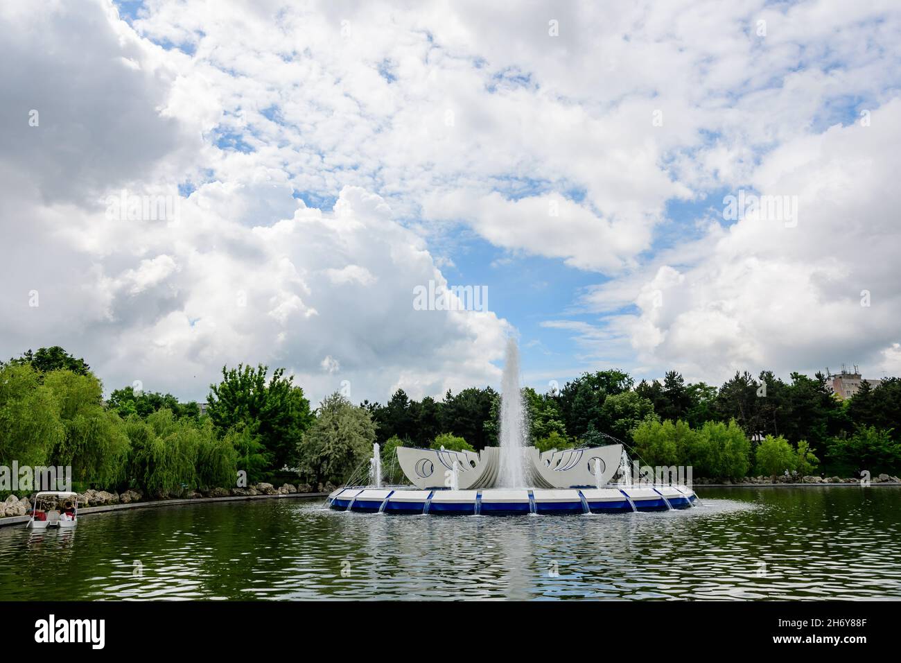 Landscape with the lake, decorative fountain and vivid green trees in ...