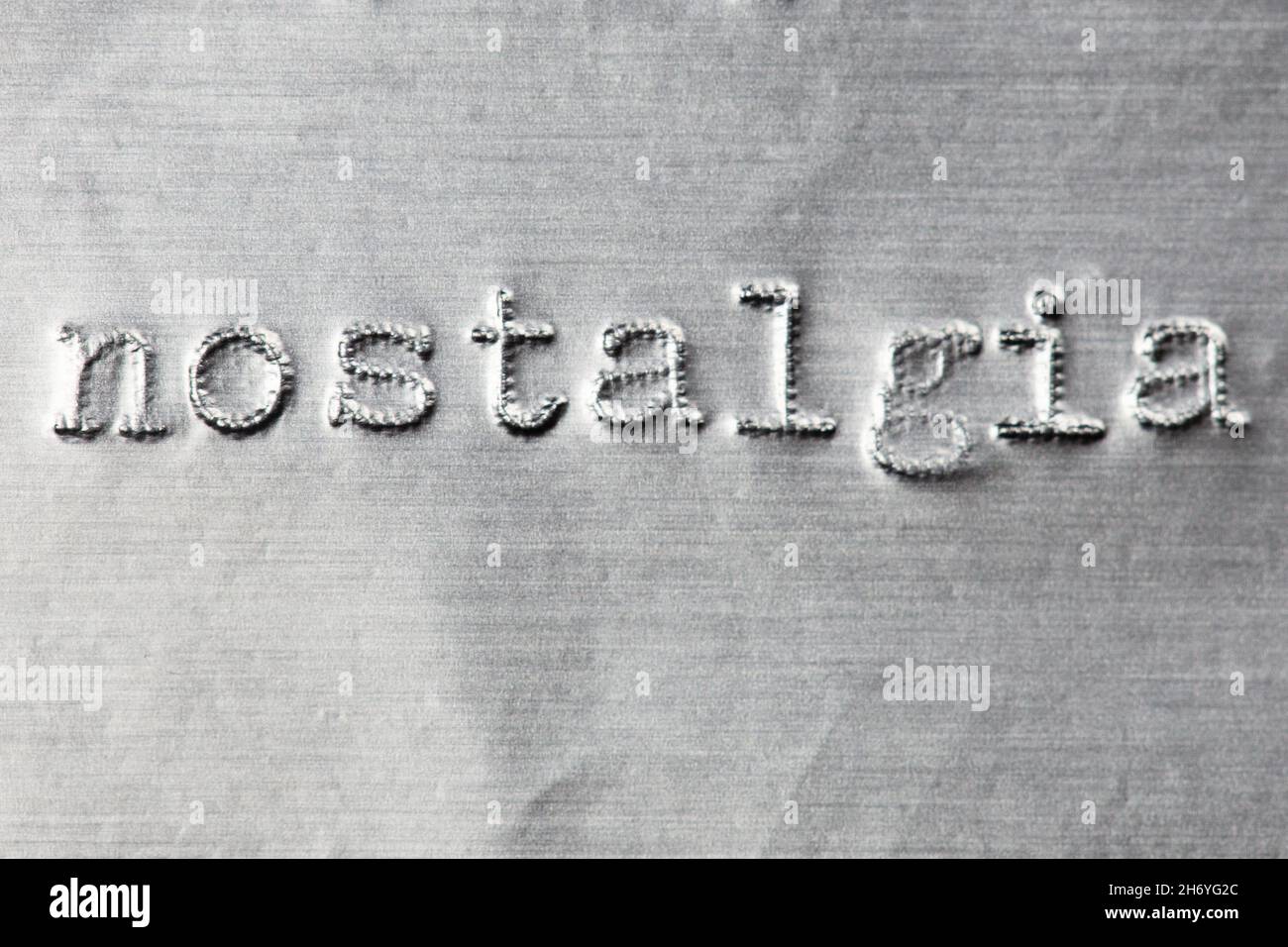 The word "nostalgia" typed with old manual typewriter onto silver ...