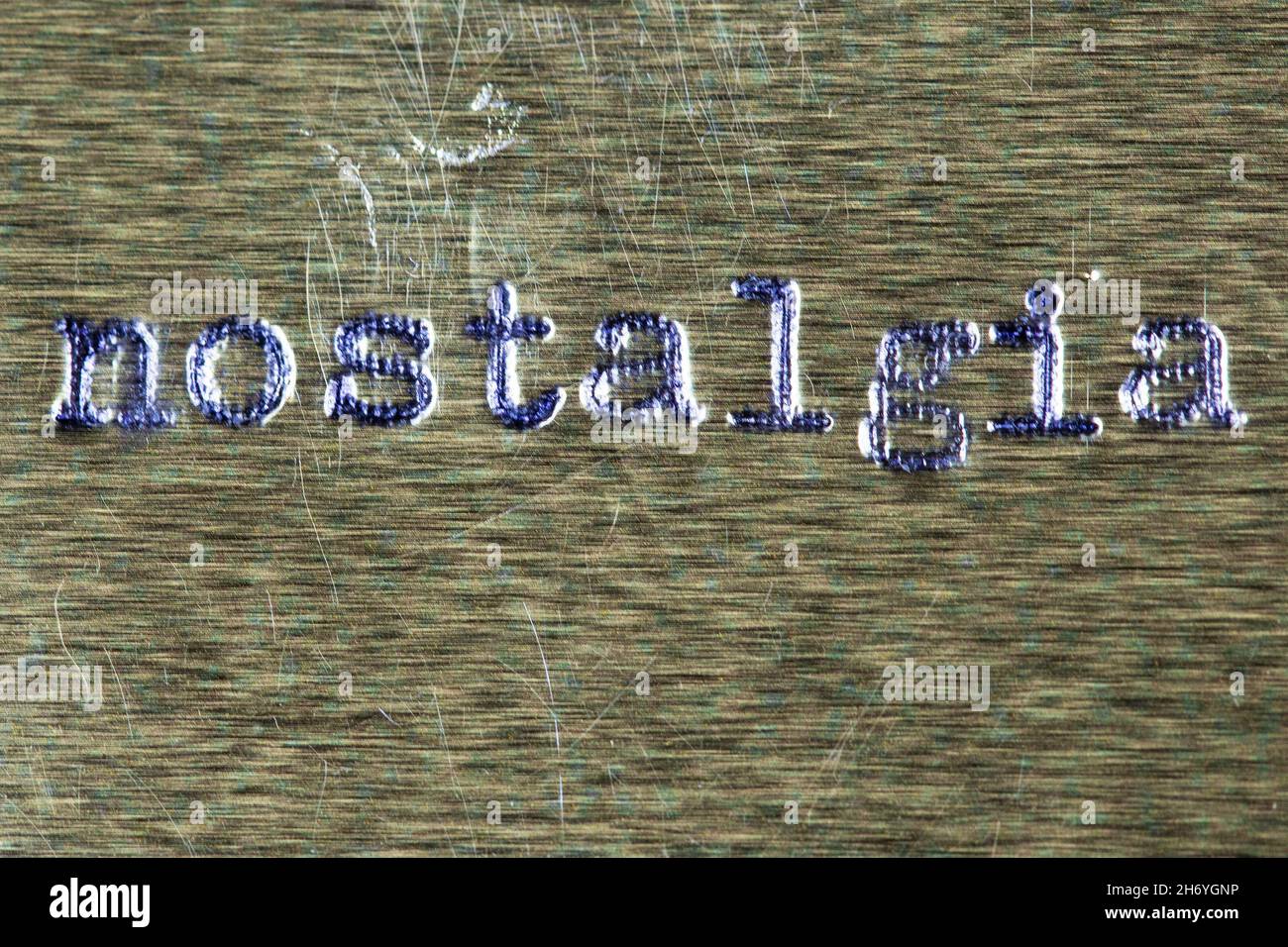 The word "nostalgia" in old manual typewriter font on a scratched and ...