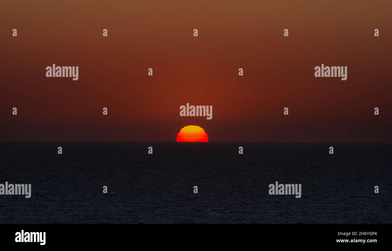 Setting sun dipping below the horizon. Surface flares possibly visible ...