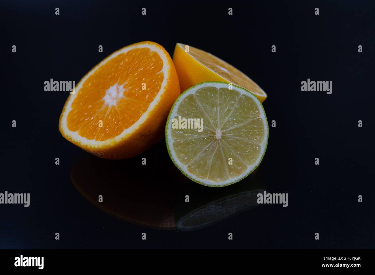 Stack of lime, orange and lemon halves on a isolated black background ...