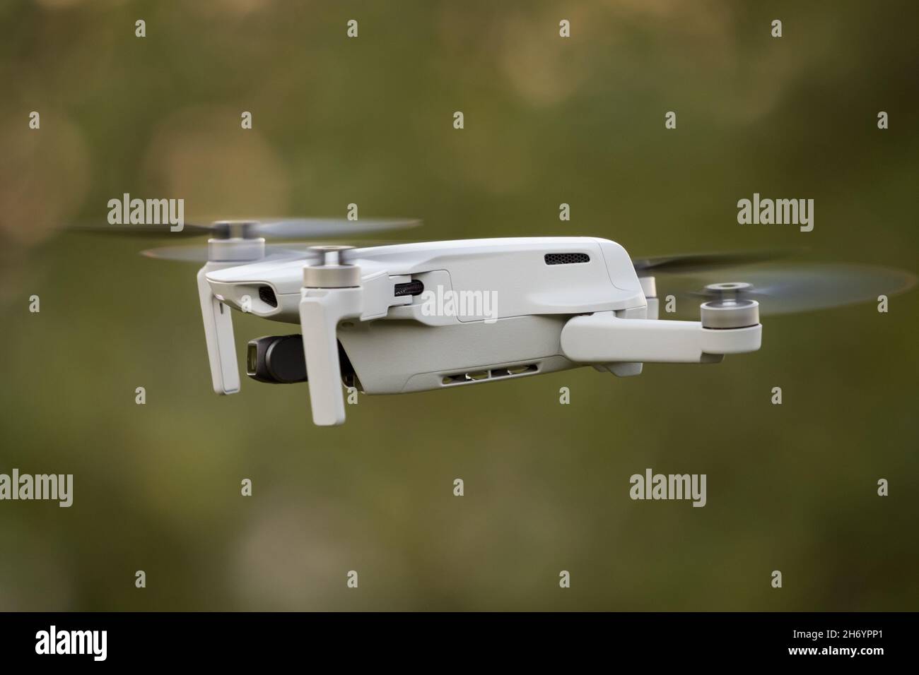 Closeup of a small white drone flying outdoors in the air with a blurry ...