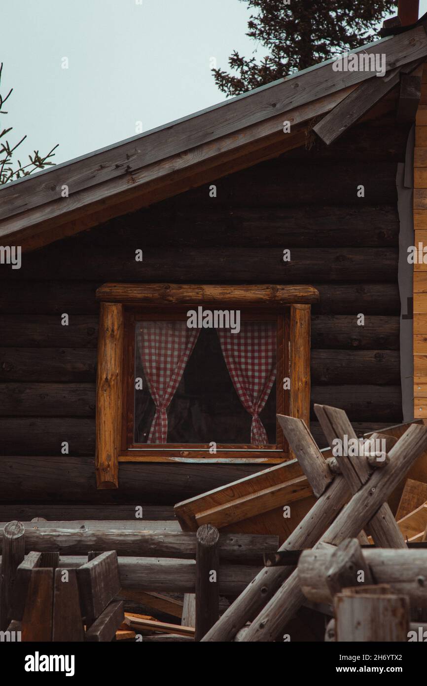 Vertical of a wooden house with a small square window with curtains in ...