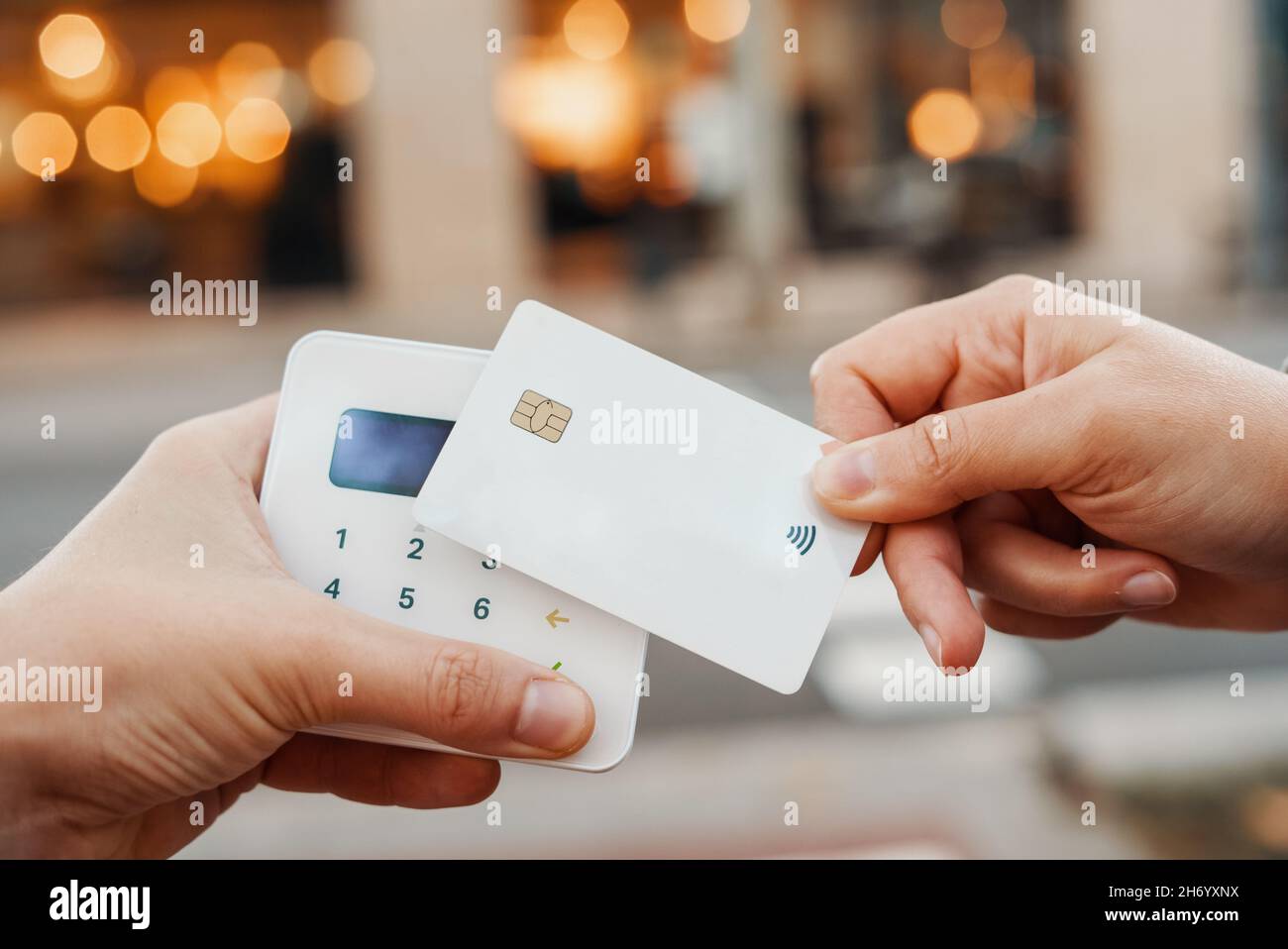 Unrecognizable customer with contactless white credit card paying to ...