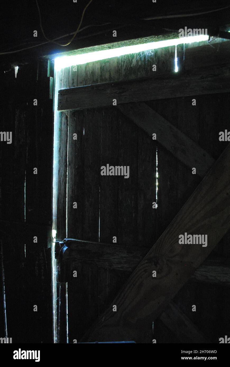 A wooden door stands ajar letting light streak through Stock Photo - Alamy