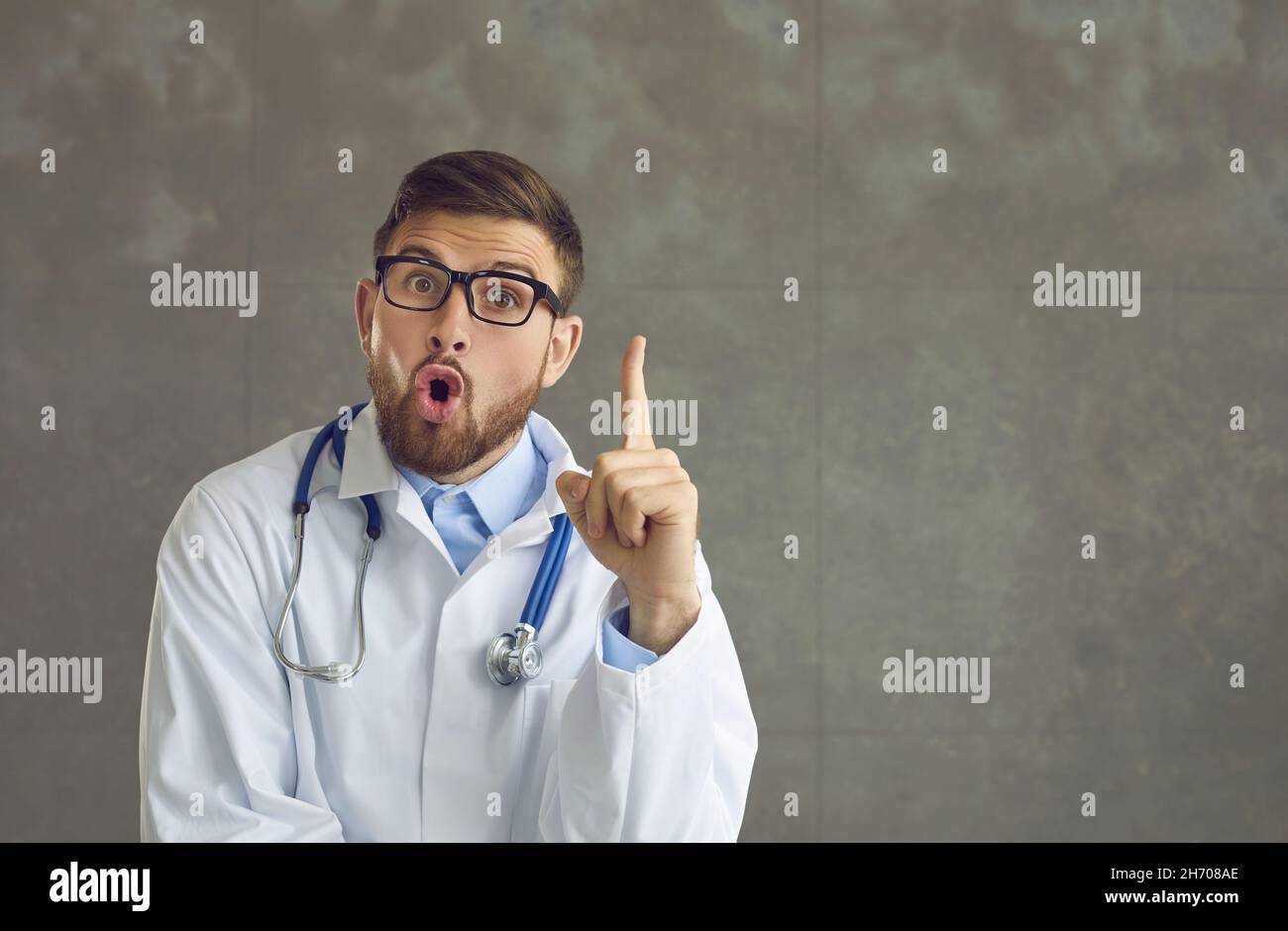 Emotional male doctor raises his finger up as a sign that he has come ...