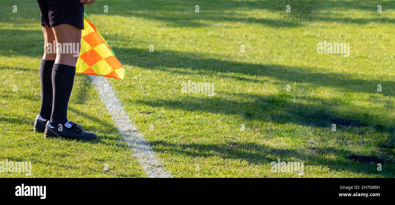 Football soccer arbiter assistant with flag at hands. Blurred green ...