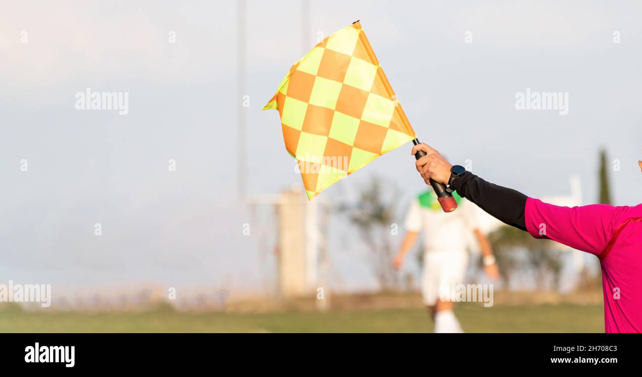 Football soccer arbiter assistant with flag at hands. Blurred green ...